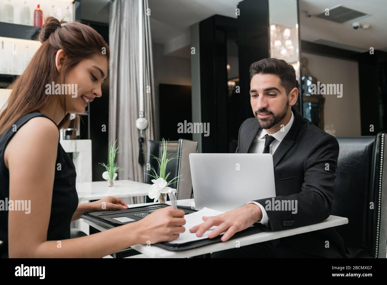 Portrait of two young business people having meeting in a hotel lobby ...