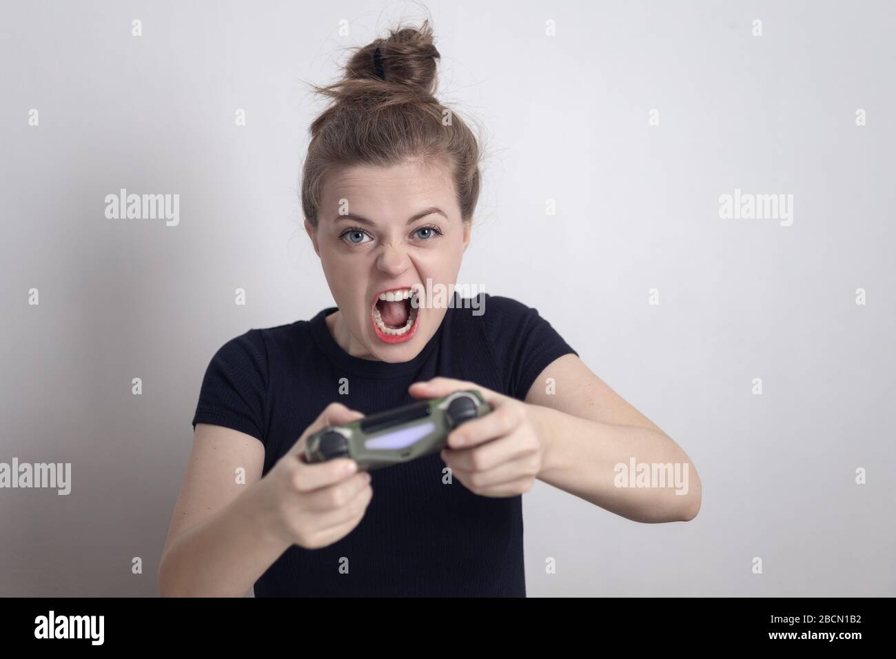 Angry young Caucasian woman girl holding joystick game pad controller ...