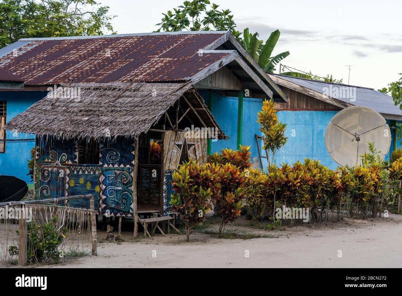 Traditional West Papuan house with a satellite dish. Colourful hut, and ...
