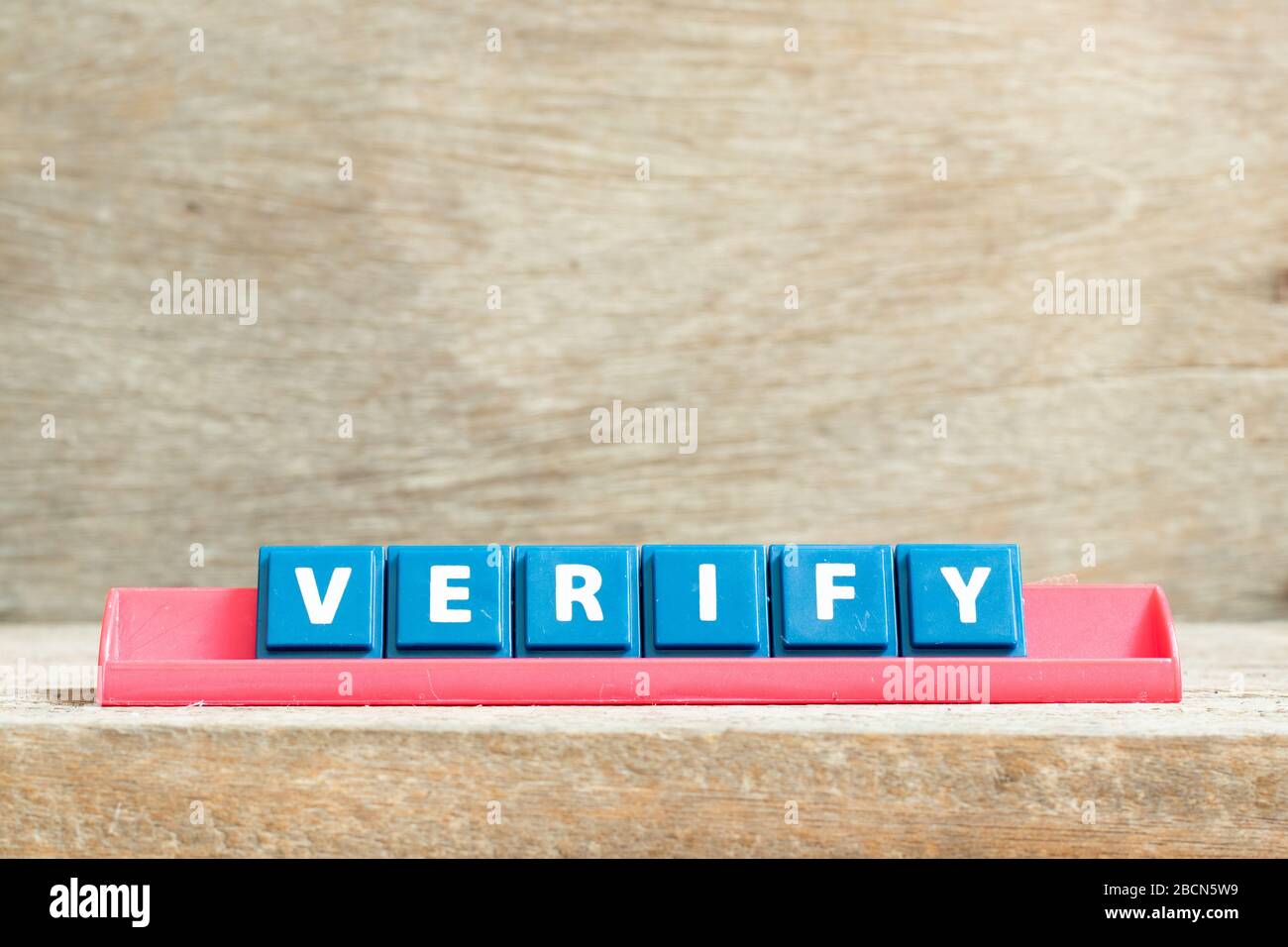 Tile letter on red rack in word verify on wood background Stock Photo ...