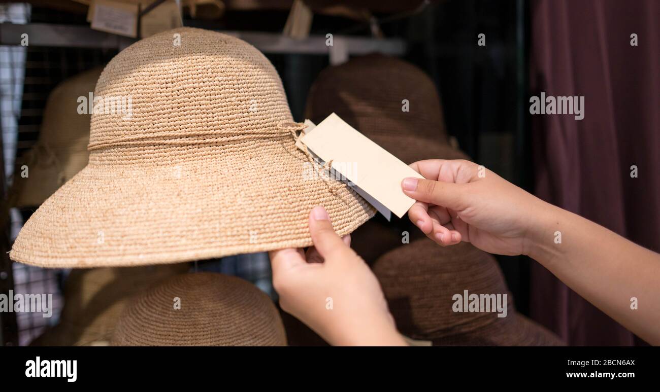 Female hand holding price tag of the fashion natural fabric hat in ...