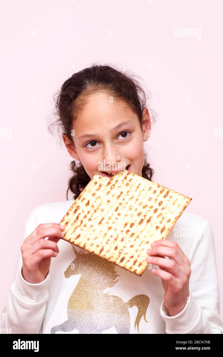 Portrait of the cute teenager girl holding matzah. Jewish child eating ...