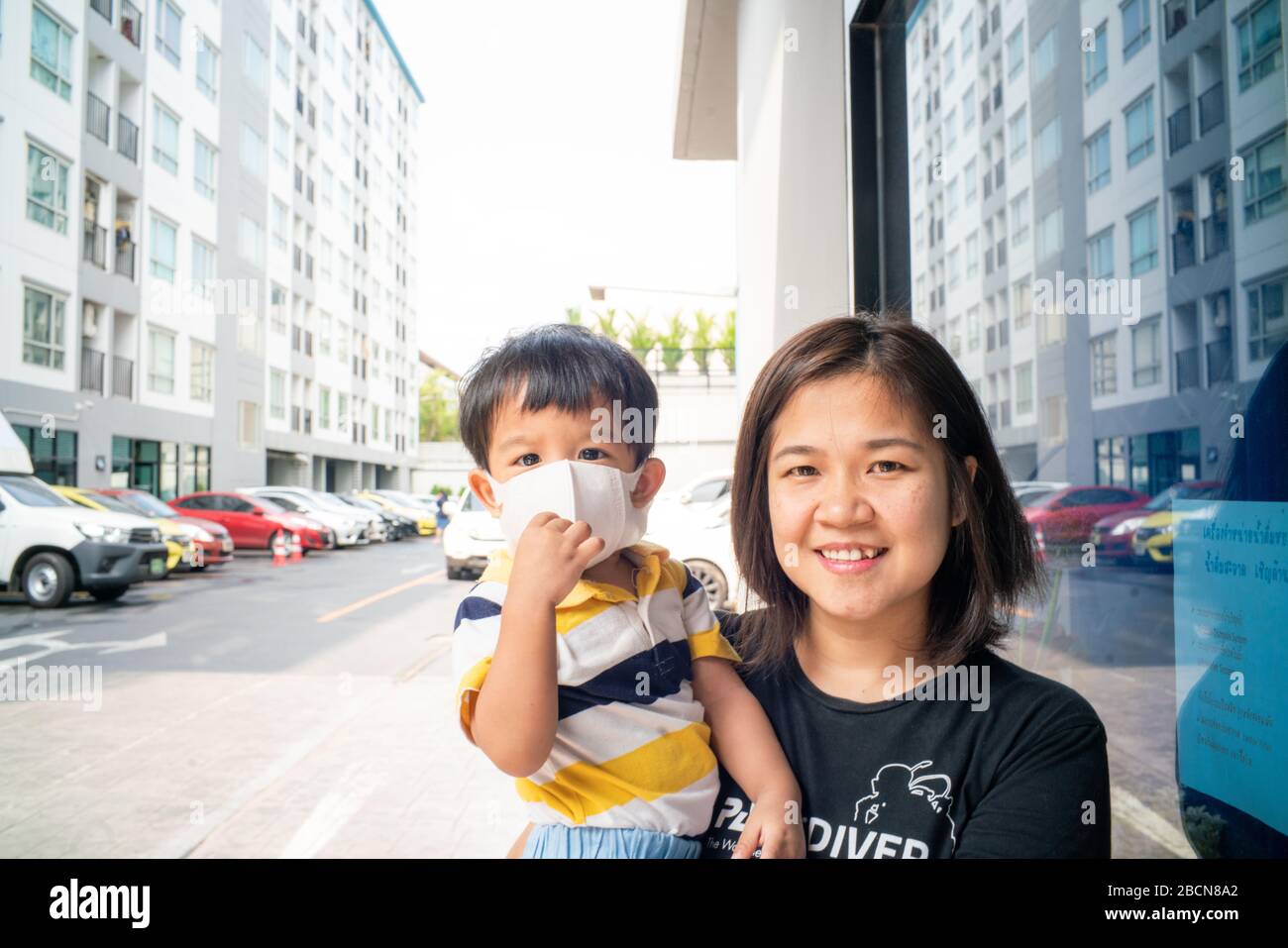 Asian cute boy and mother wearing N95 mask outdoor city building ...