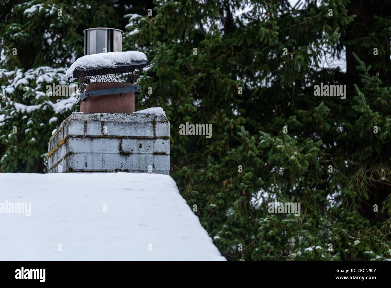 Residential house rooftop covered in snow, close-up of brick chimney ...