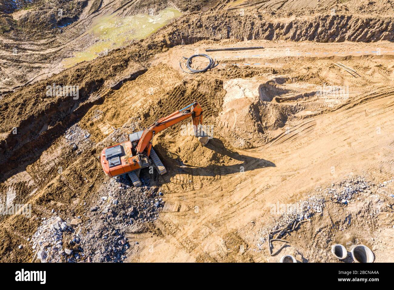yellow backhoe moving ground on construction site. top down aerial view ...