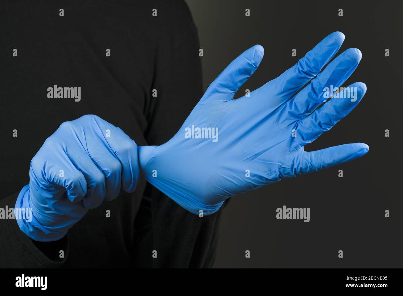 Putting on blue rubber hand gloves. Wearing protective hand gear ...