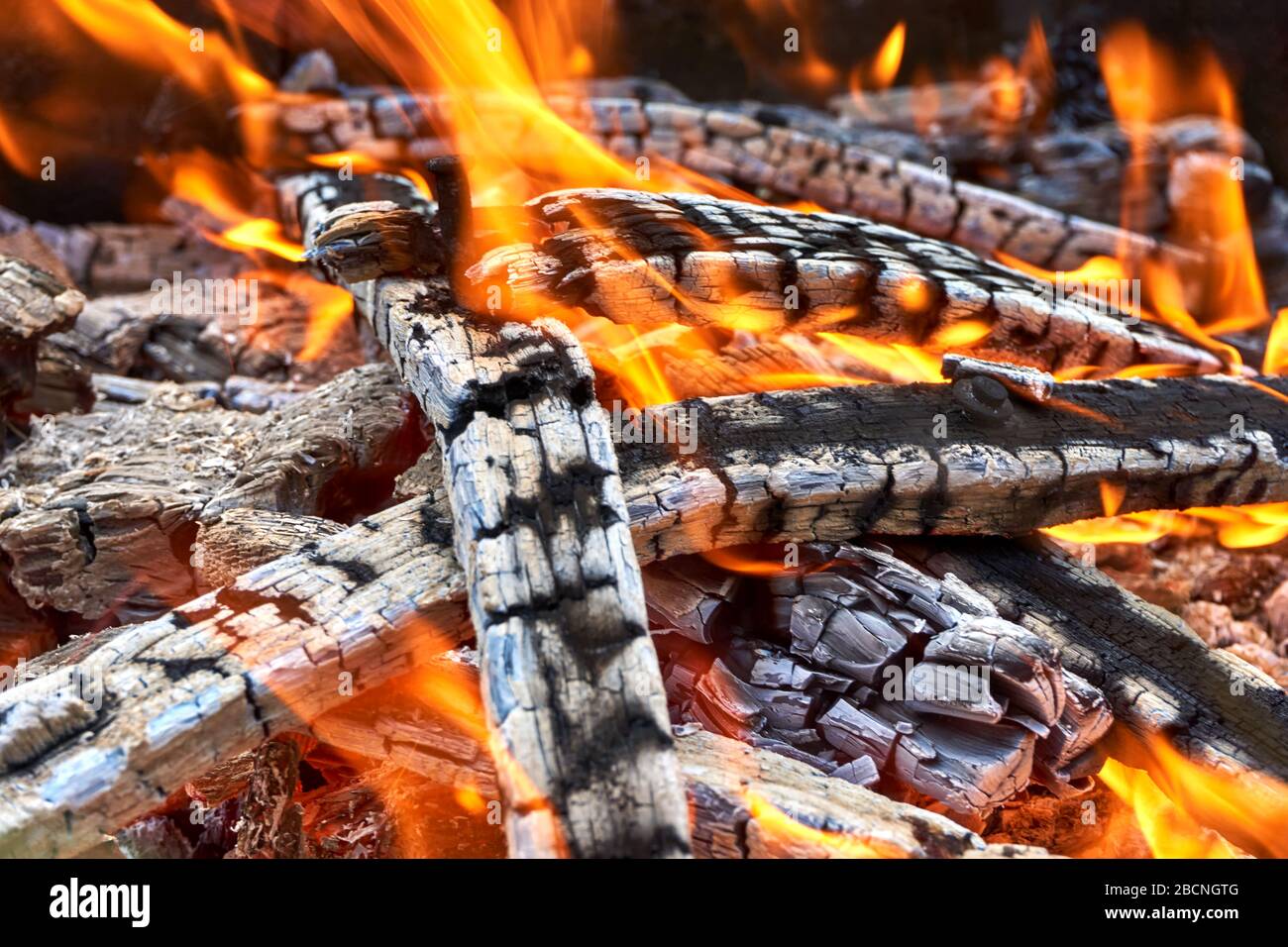 Wood fire background. Black burnt wood with orange flames and embers ...