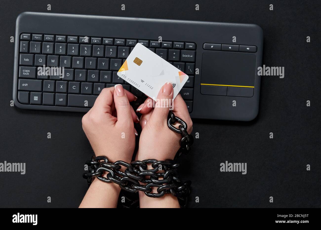 Woman with metal chain holding credit card over keyboard, online ...