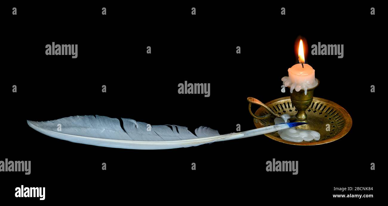 Creativity concept with a white feather and burning candle in copper ...