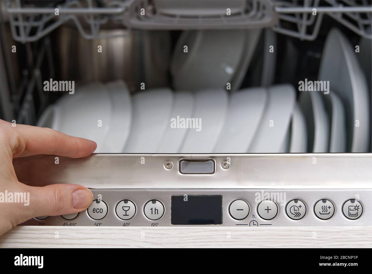 Full loaded Dishwasher machine. Integrated Dishwasher with white plates ...