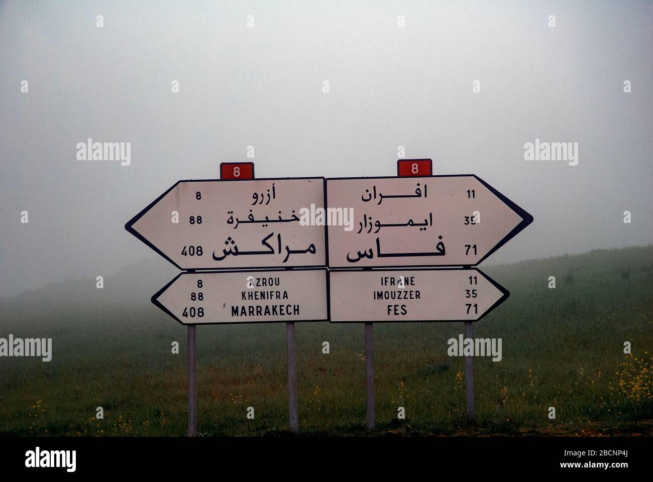 Road sign in misty Moroccan countryside .Left to Marrakech .Right Fes ...