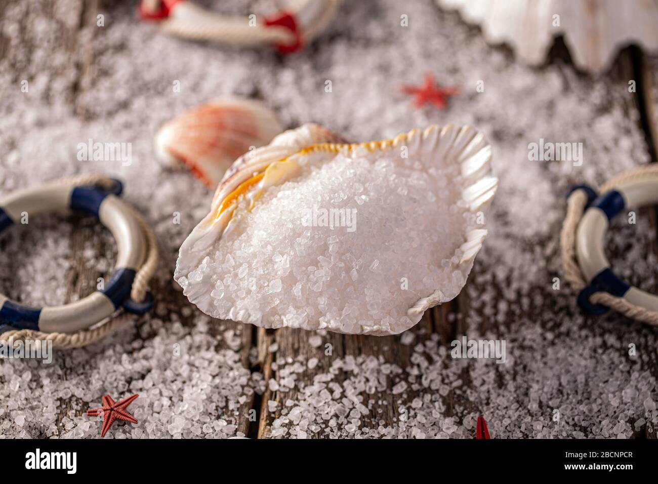 Sea salt crystals in the sea shell on wooden background Stock Photo - Alamy