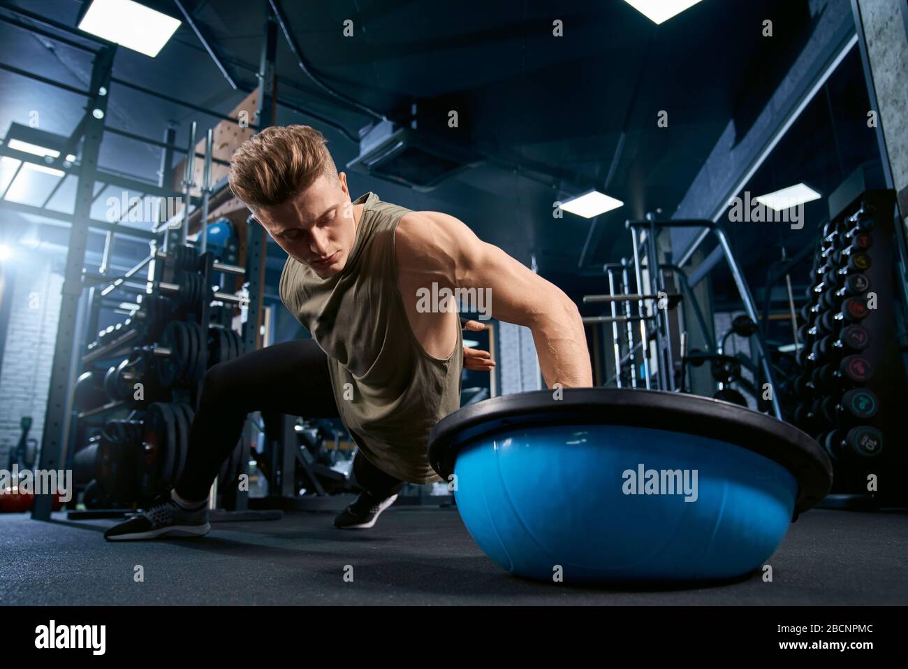 Front view of muscular caucasian man doing push ups on one hand on ...