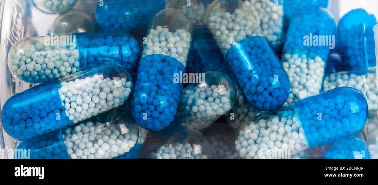 Many blue white two color transparent supplement pills with granules ...
