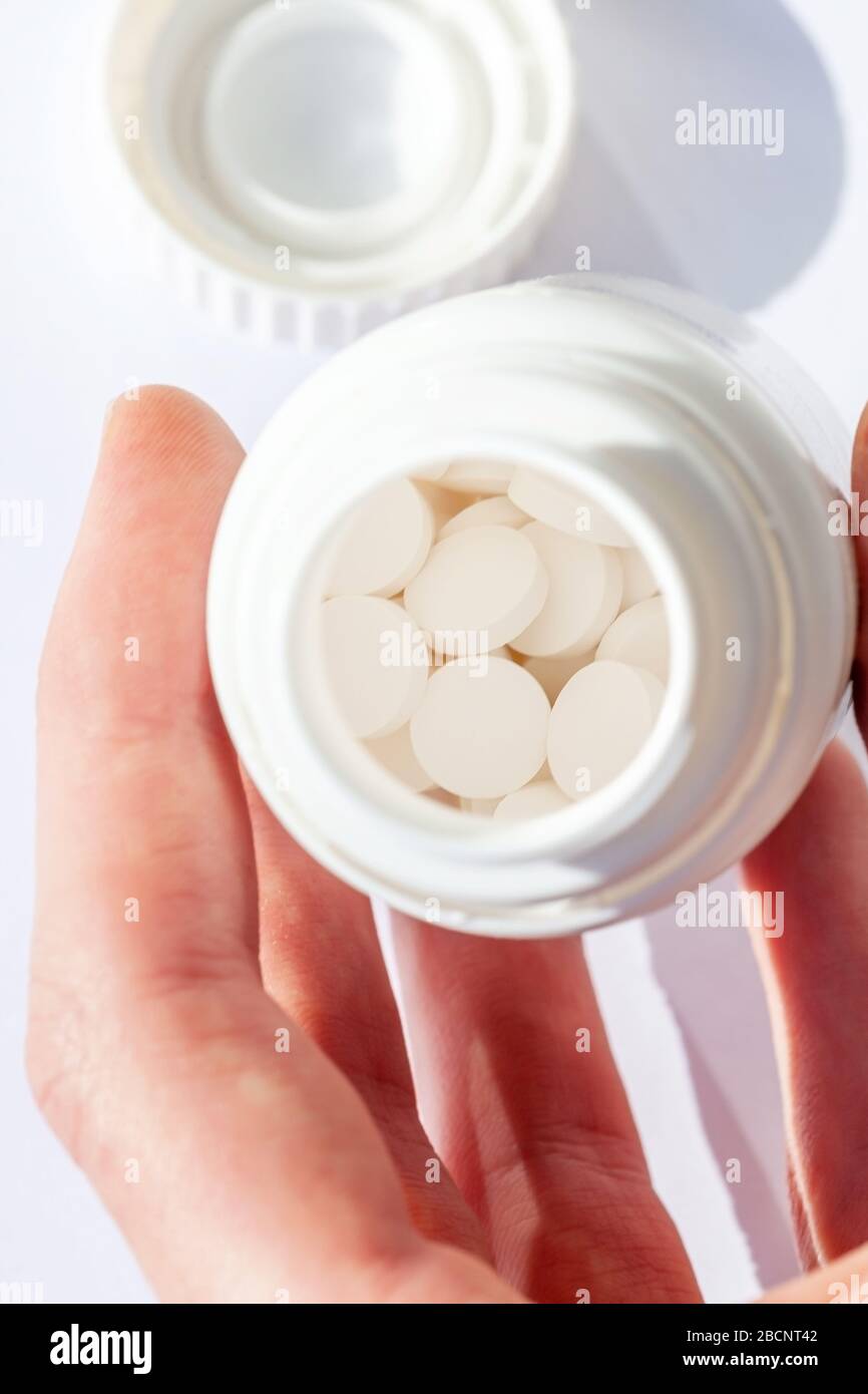 Man looking into a small open pill container with white pills inside in ...