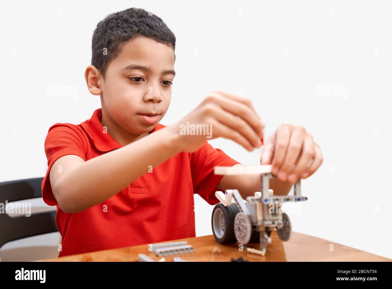 Front view of lovely conentrated african boy sitting at table and using ...
