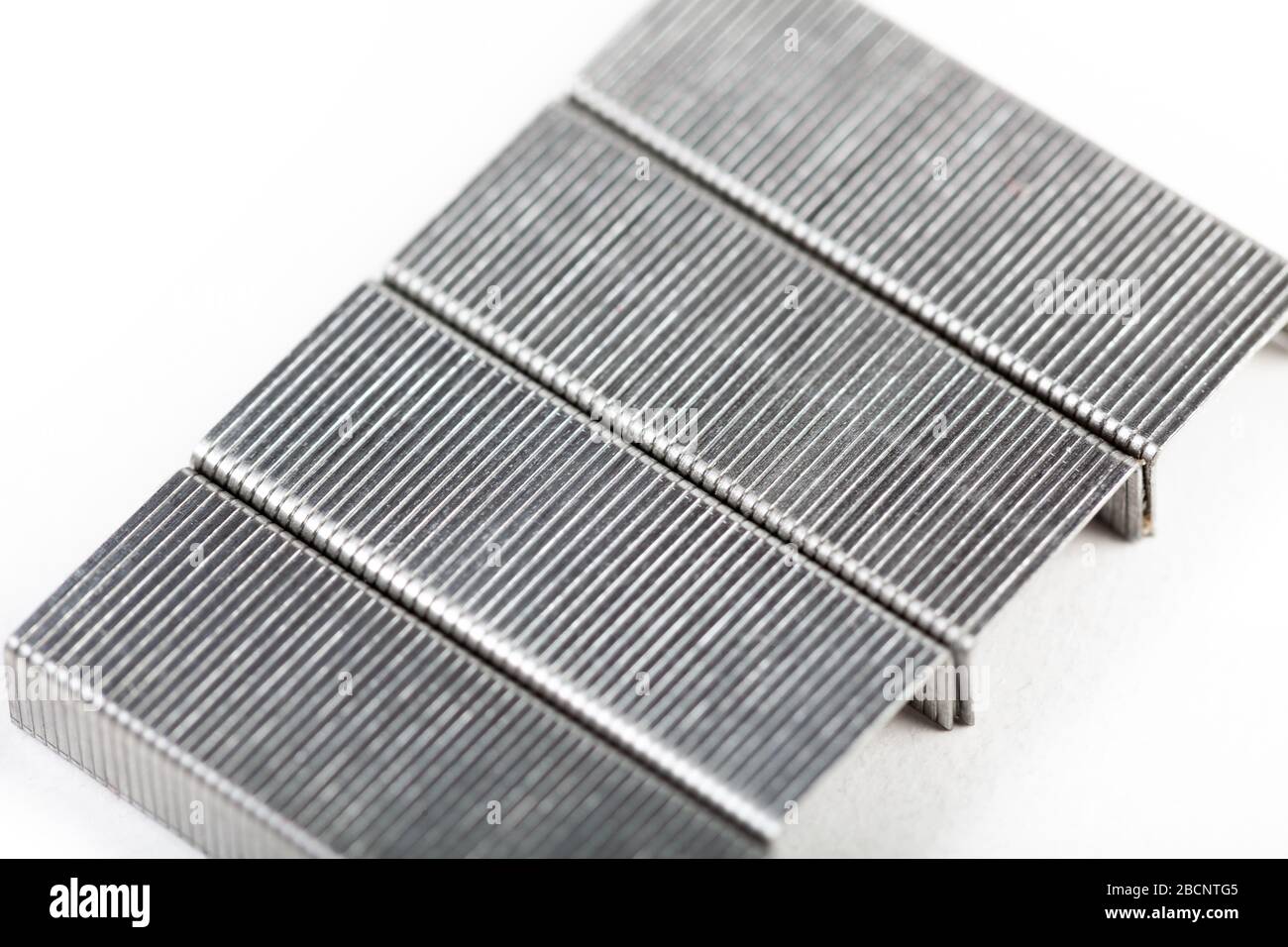 A set of silver metal staples on white, top view, closeup. Office ...