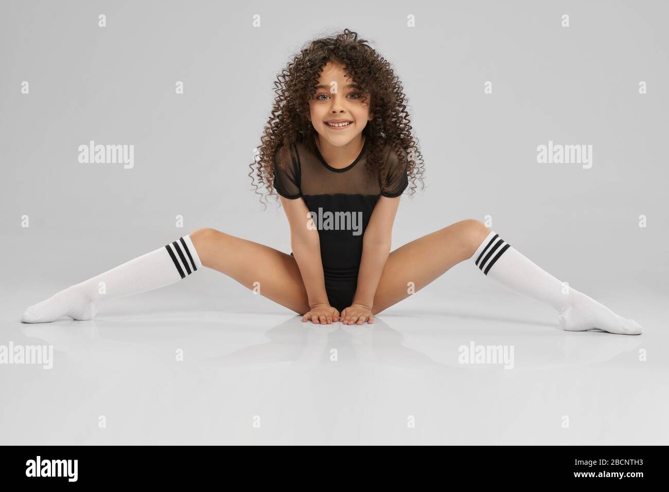 Smiling Girl In Black Sportswear And Knee Socks With Curly Hair Showing