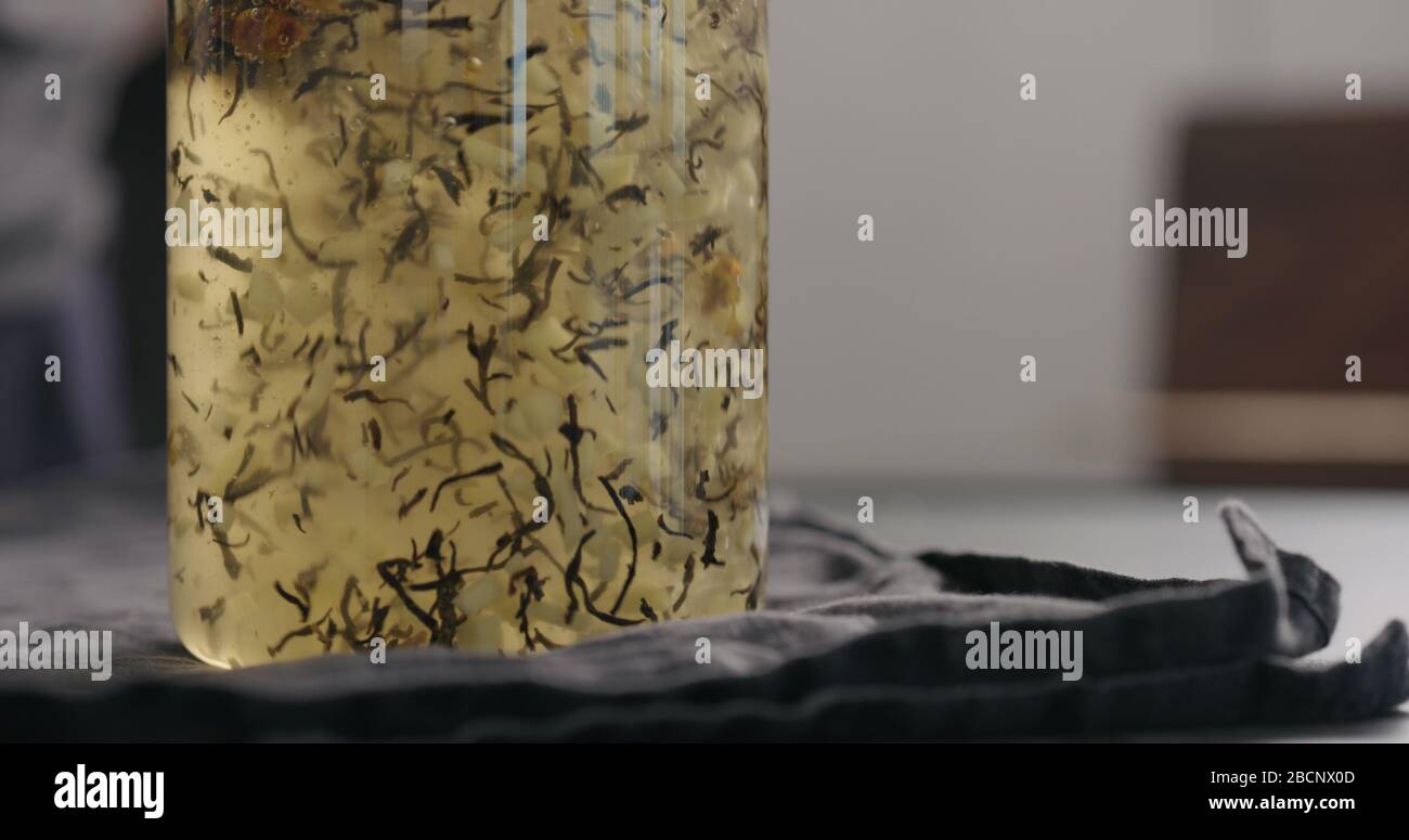 pour black tea with ginger and seaberry with hot water in glass beaker ...