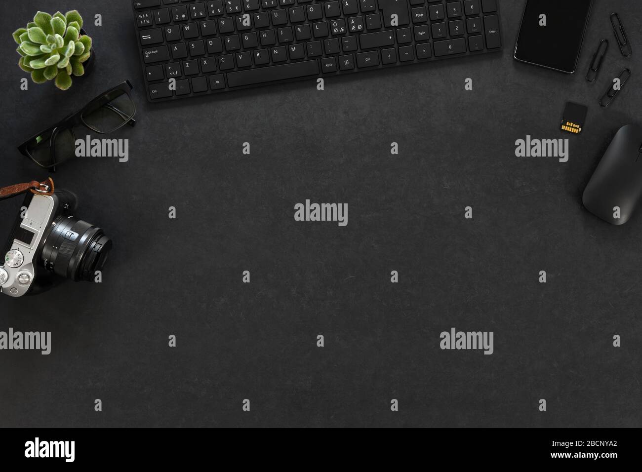 Top view of black concrete office desk with computer, camera and ...