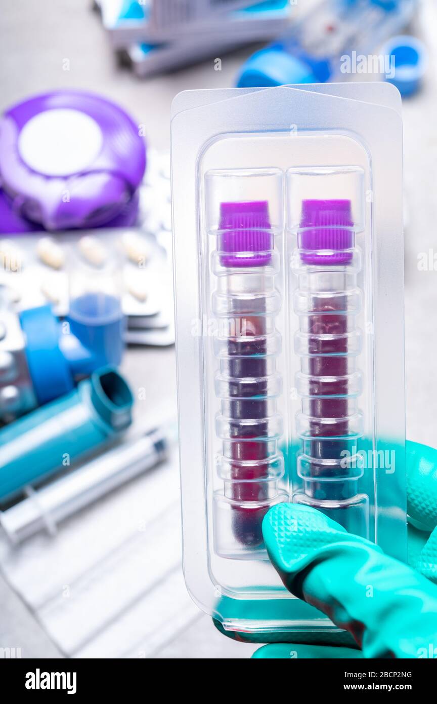 Hand with two medical test-tubes with blood samples for screening of ...