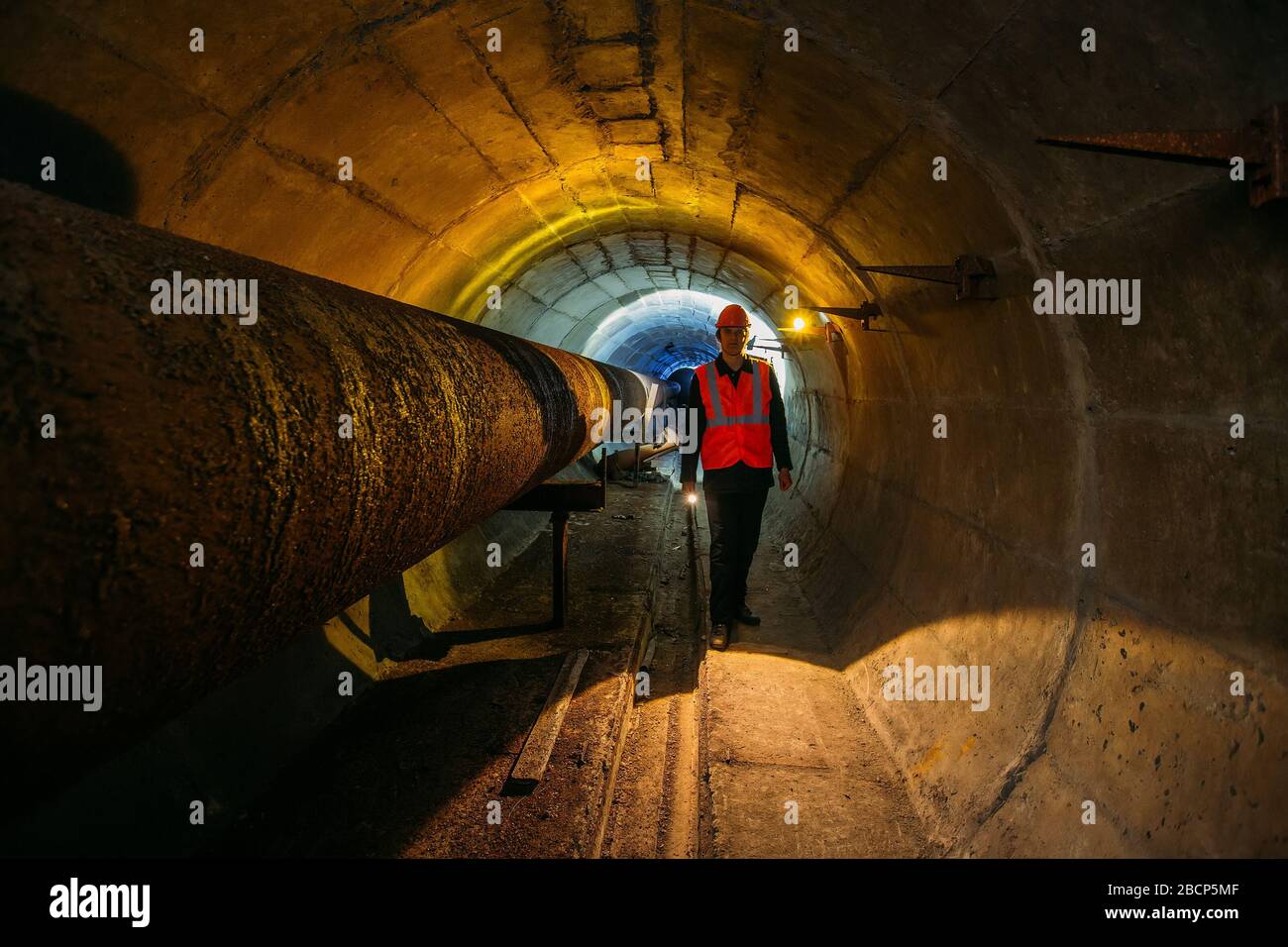 Tunnel worker examines pipeline in underground tunnel Stock Photo - Alamy
