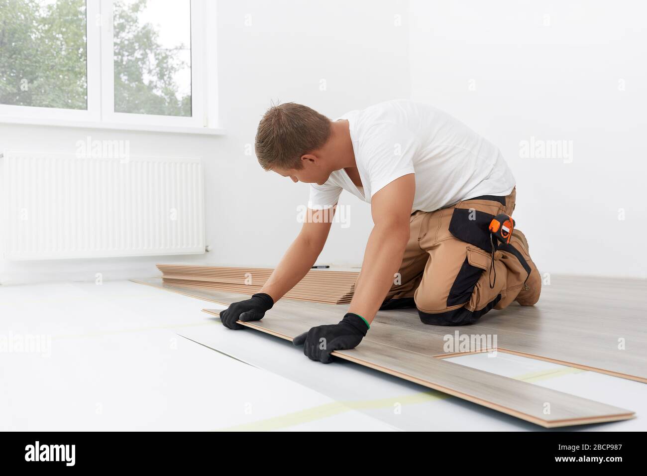Male worker installing laminate flooring. Longitudinal lock joint - The ...