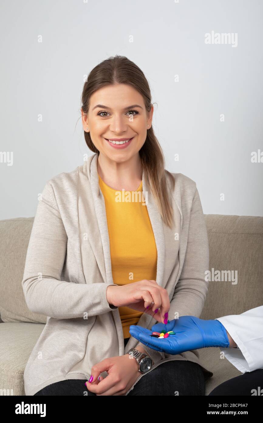 Young female patient sitting on the couch receiving medication from ...