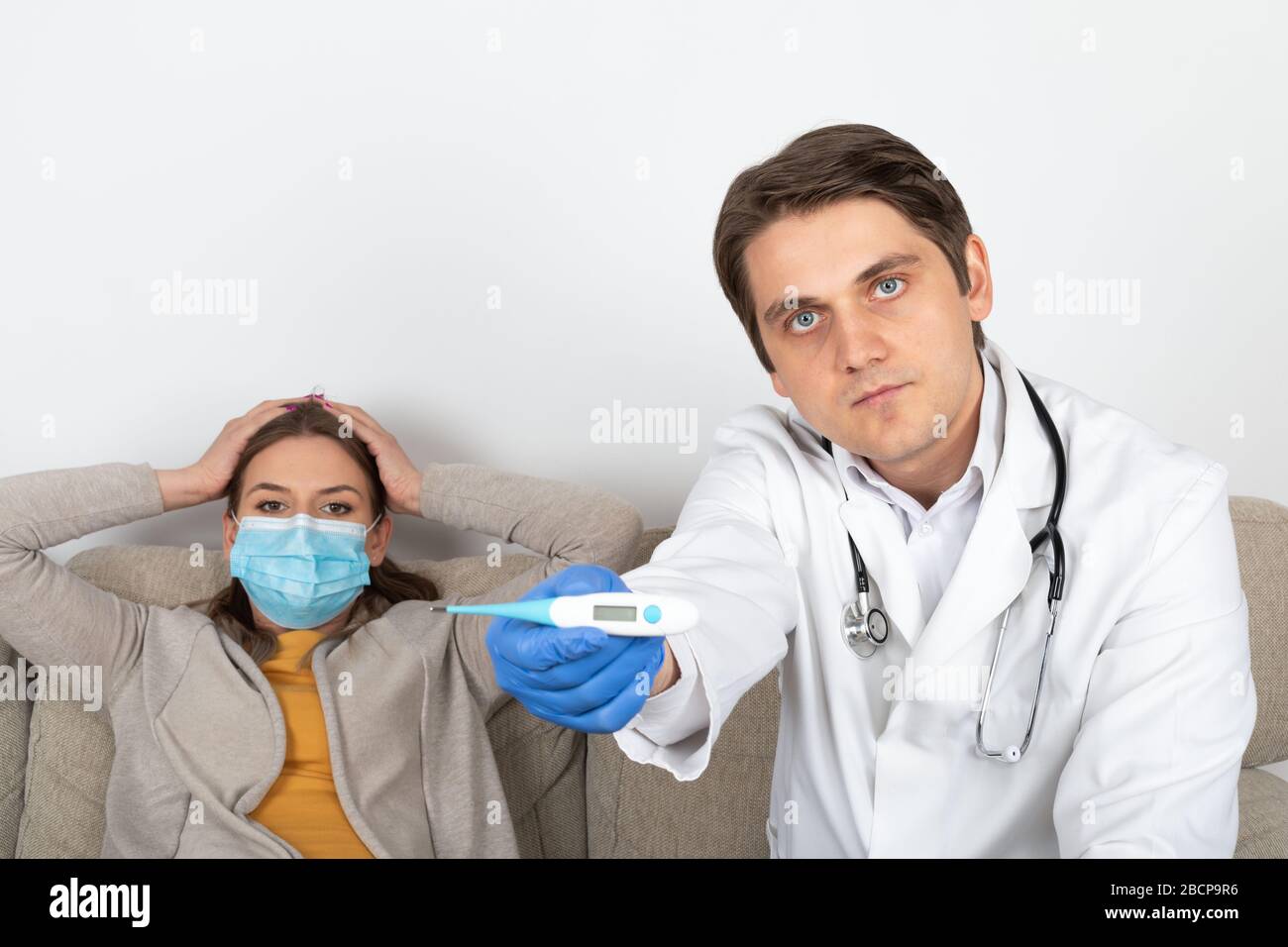 Young male doctor consulting female patient with influenza symptoms at ...