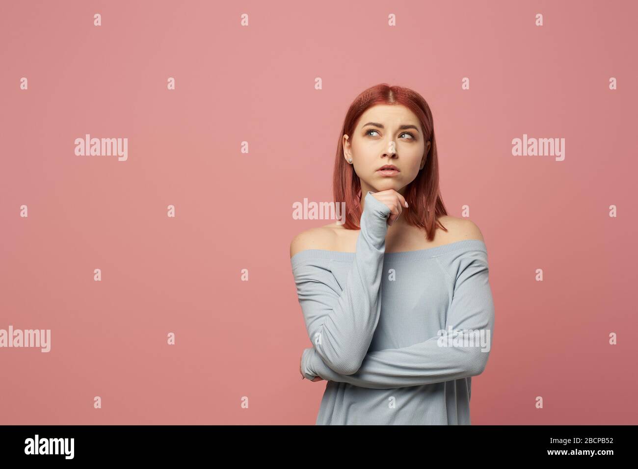 Sad ginger woman standing in studio on isolated pink background Stock ...