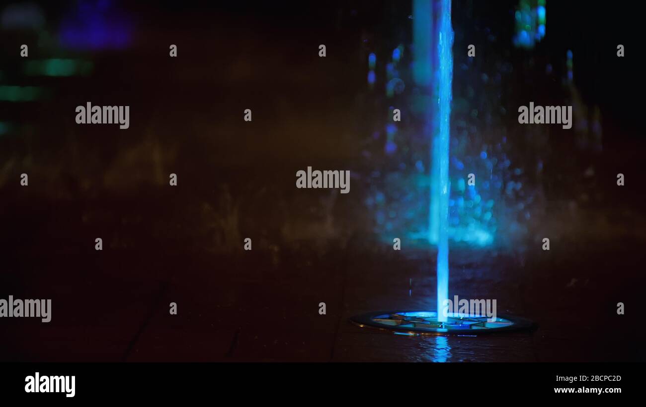 Splashes of colorful fountain. Water illuminated in diverse colors ...