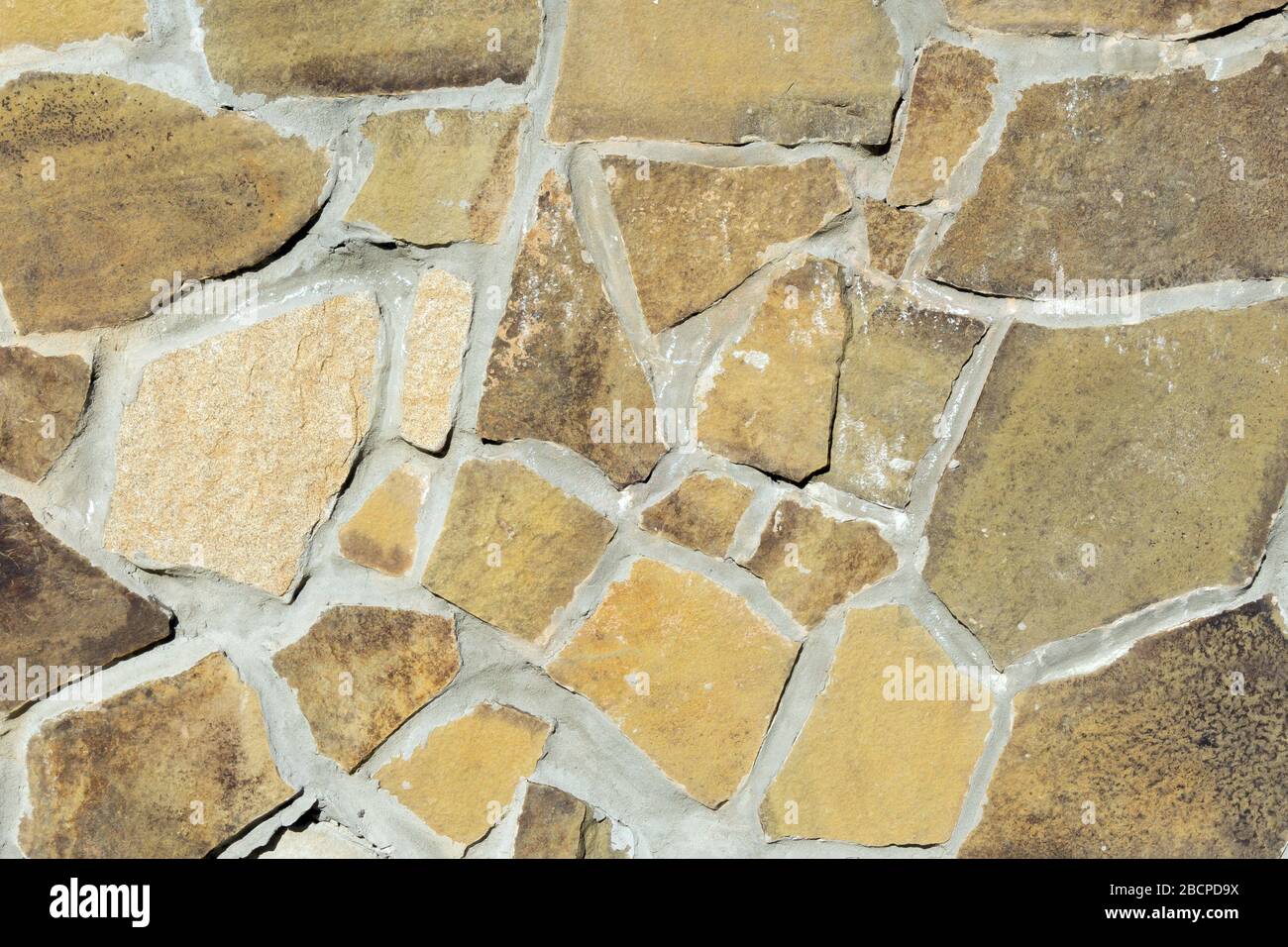 textured wall made of rectangle shaped, rough, uneven stones of reddish ...