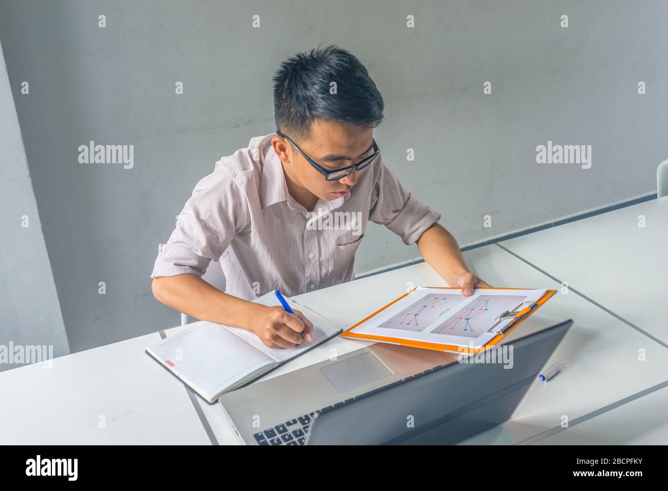 Office employee reading financial document and writing note Stock Photo ...