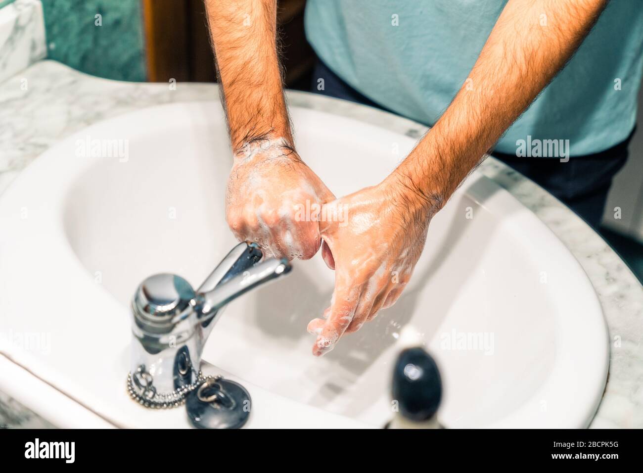 Washing your thumb thoroughly with disinfectant soap in the sink to ...