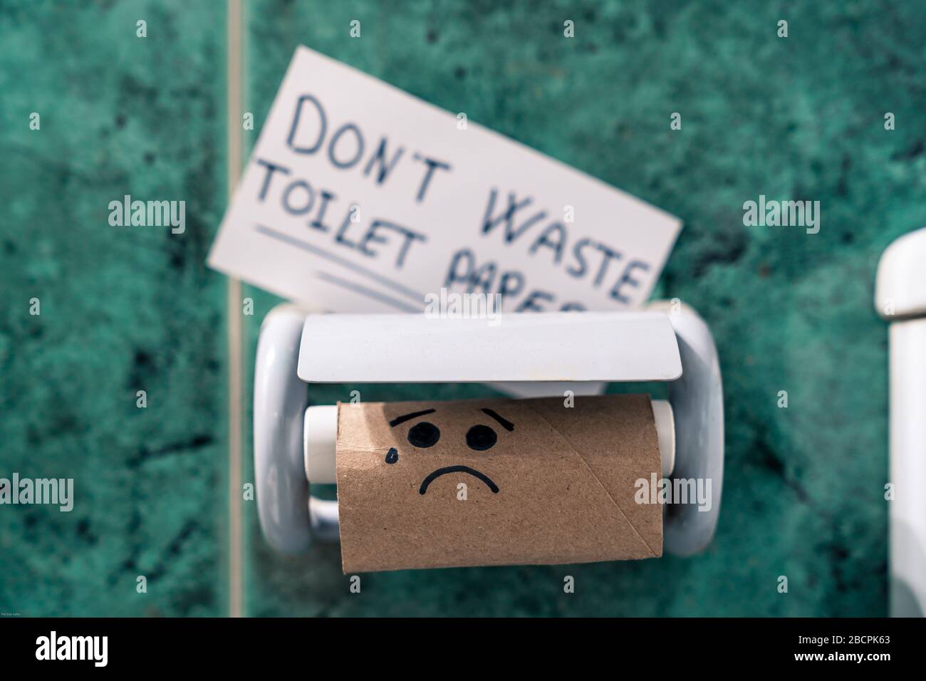 Toilet paper roll finished in the bathroom with a picture of a sad face ...