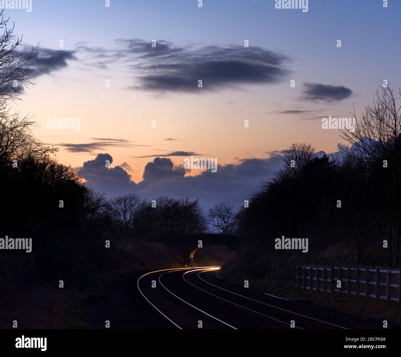 Train headlights from a approaching train illuminate the railway track ...