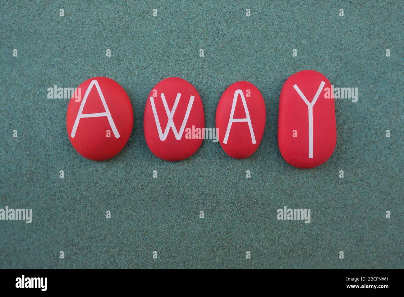 Away text composed with red colored stone letters over green sand Stock ...