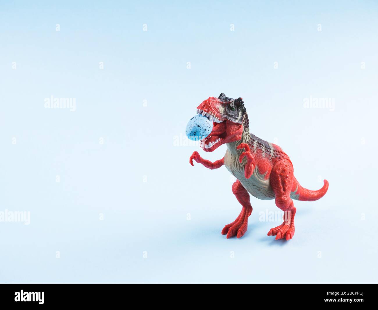 Angry dinosaur toy with easter egg in mouth Stock Photo - Alamy