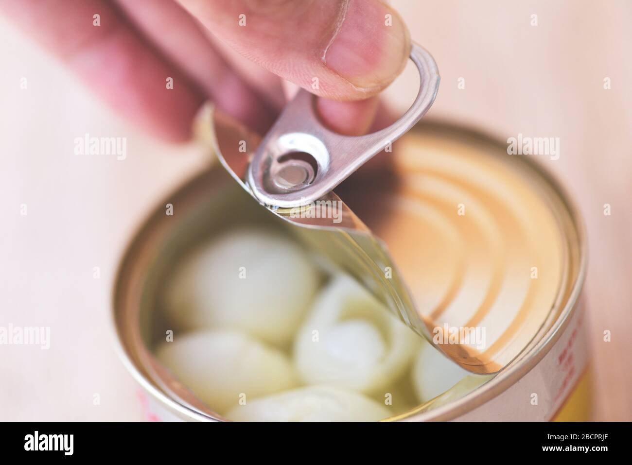 Hand open canned food in metal can on wooden background / Close up ...