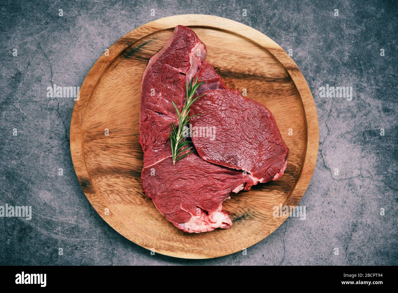 Fresh beef animal protein / Raw beef meat wite rosemary on wooden plate ...