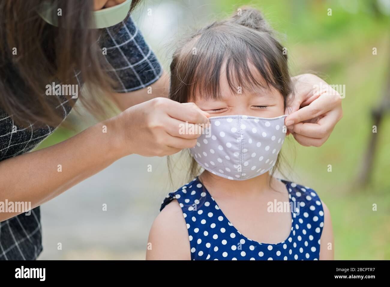 Mother is wearing a cloth mask for little girl protect herself from ...