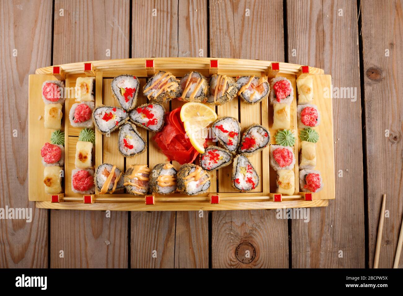 large colorful set of sushi in a square plate. on a wooden background ...
