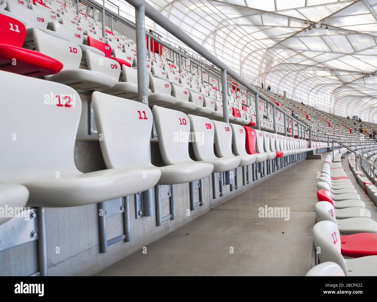Rows of plastic seats in a sports stadium. The seats are red and white ...