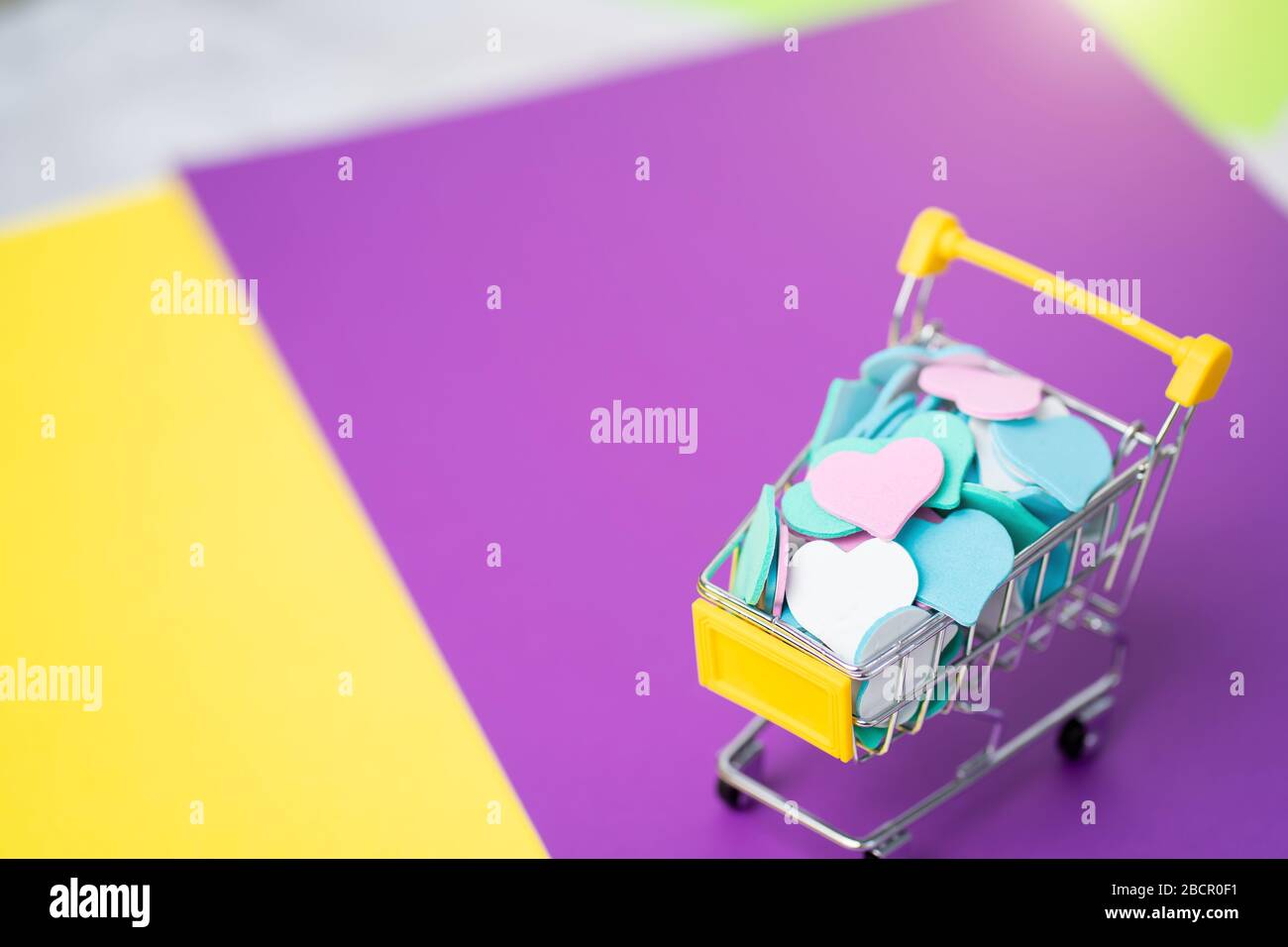Closeup miniature cart with small multicolored hearts on paper two ...