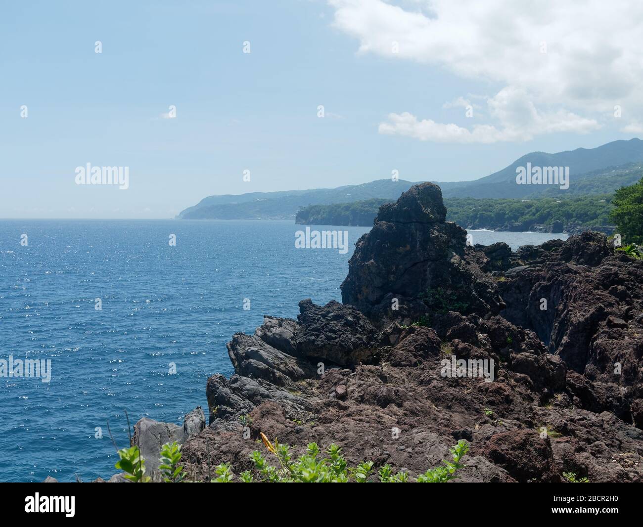 View of volcanic rocky coast and the sea with reflection of the ...