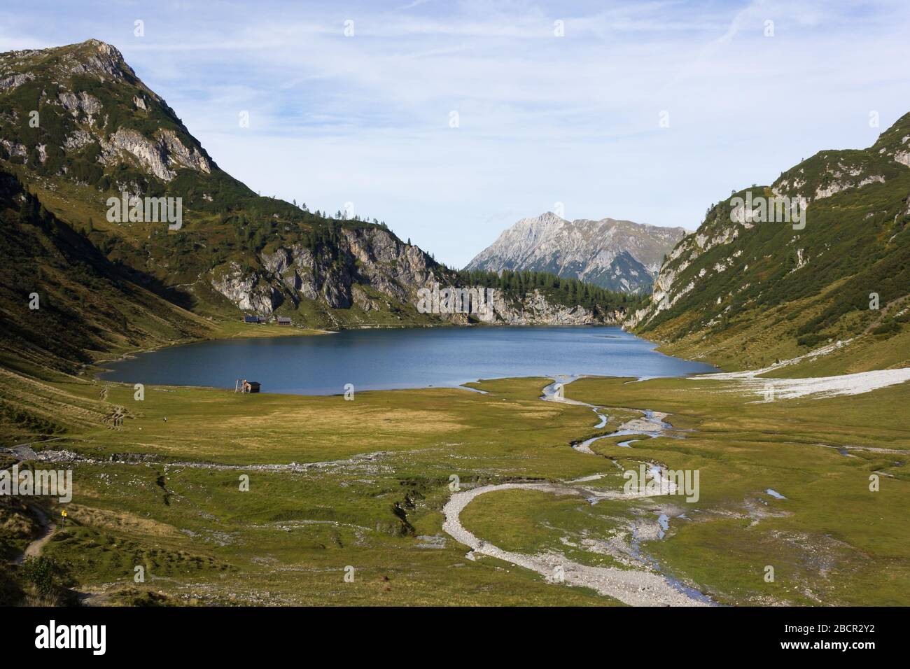 Alpine mountain lake with small meandering stream in the Austrian Alps ...