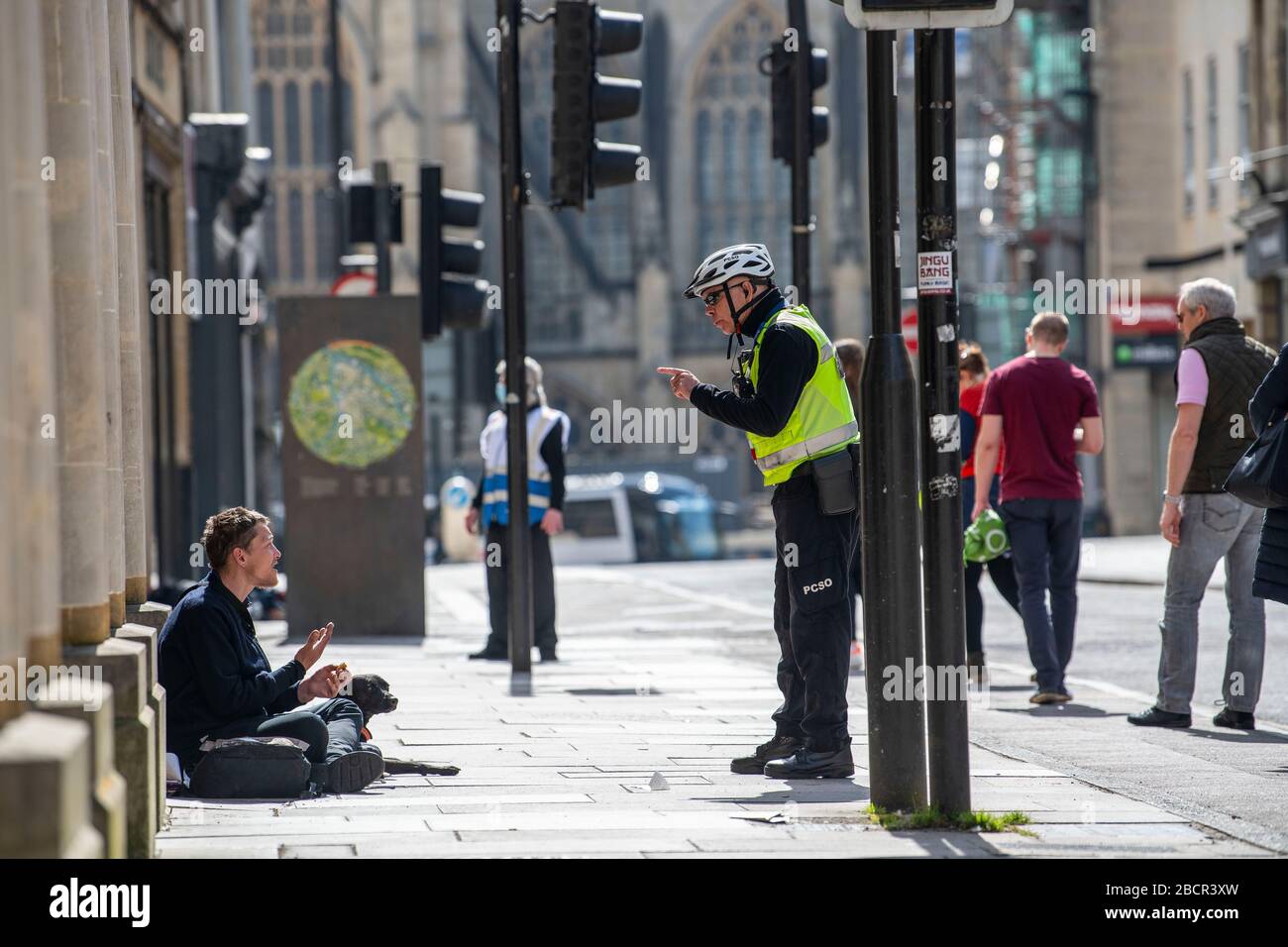 A police officer speaks to a man begging outside a supermarket in Bath ...
