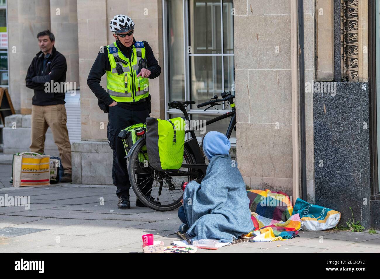 A police officer speaks to a woman begging outside a supermarket in ...