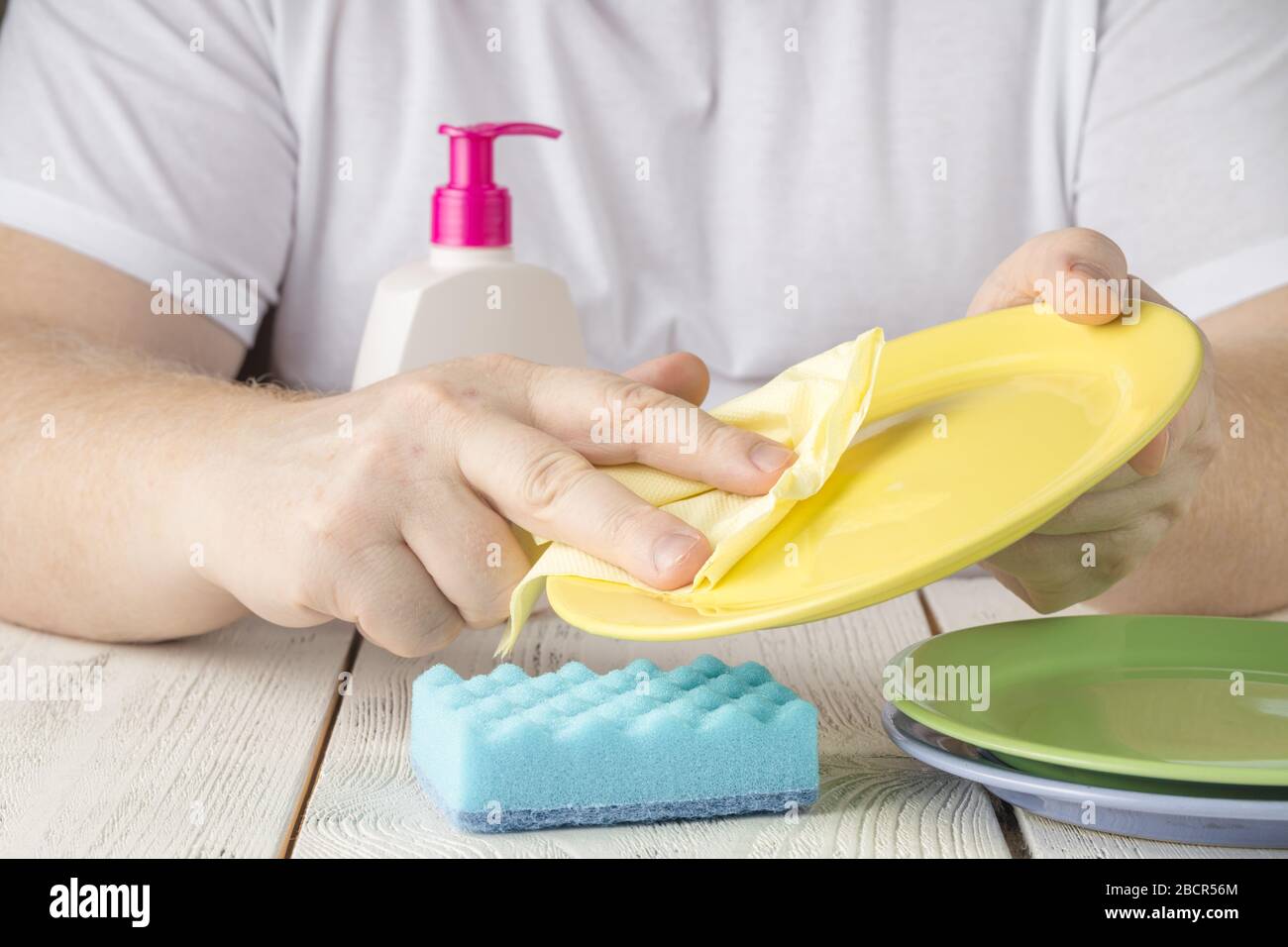 Close up mans hand wipe with towel a clean plate after washing all the ...