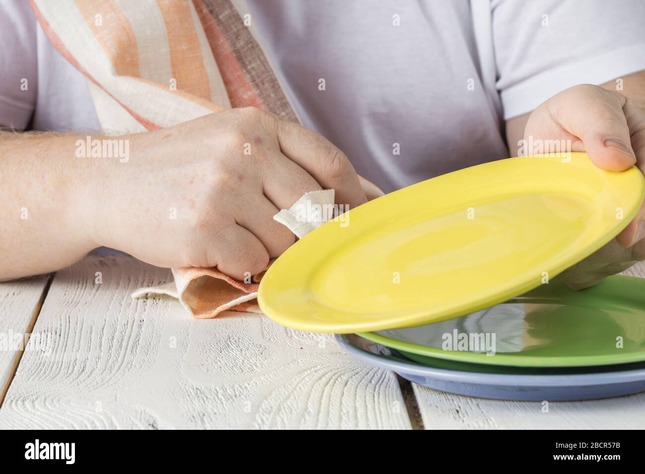 Close up mans hand wipe with towel a clean plate after washing all the ...
